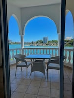 Varanda com vista para a água, uma mesa e cadeiras de vime.