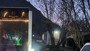 Uma placa de boas-vindas a uma cabana de madeira, com um caminho que leva à entrada.