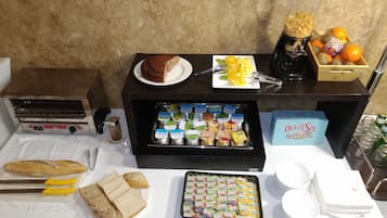 Buffet com diversos alimentos, incluindo pão, doces e acompanhamentos.