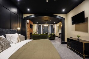 Quarto moderno com cama grande, televisão na parede e lareira.