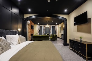 Quarto moderno com cama grande, televisão na parede e lareira.
