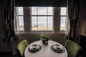 Mesa de jantar com vista para a praia através de grandes janelas.