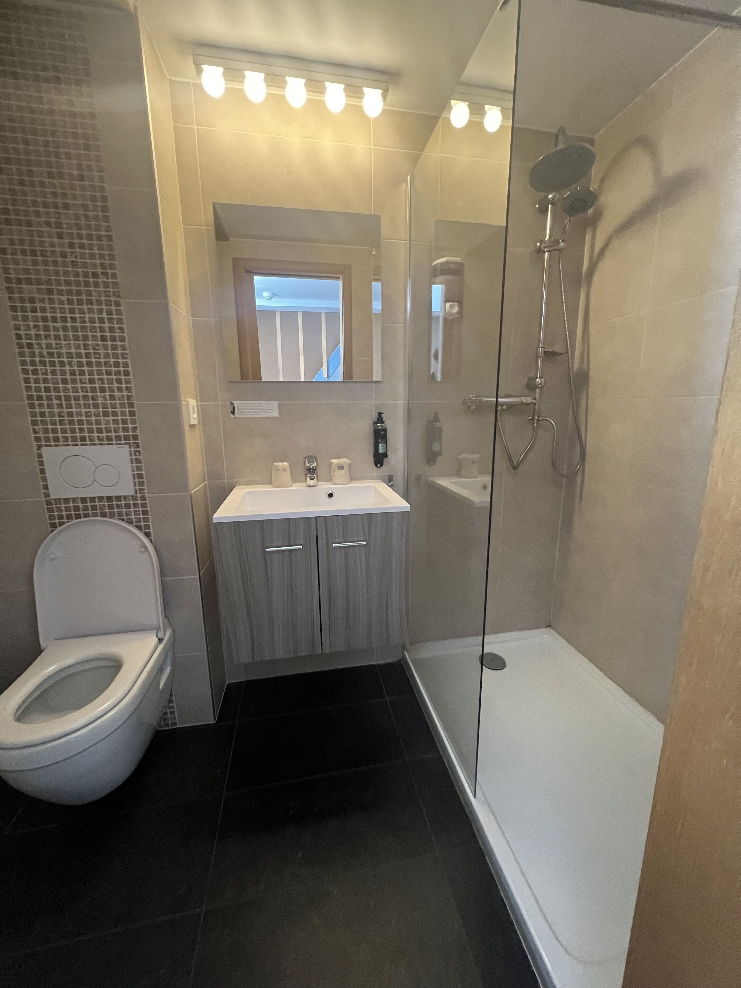 Uma casa de banho moderna com sanita, lavatório e cabine de duche envidraçada.