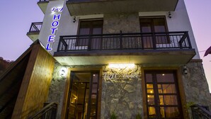 Um hotel de vários andares com fachada de pedra, detalhes em madeira e varandas nos andares superiores.