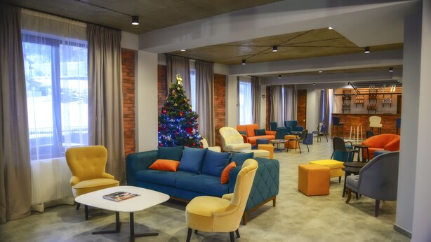 Um hall amplo com árvore de Natal, assentos confortáveis e área de bar.