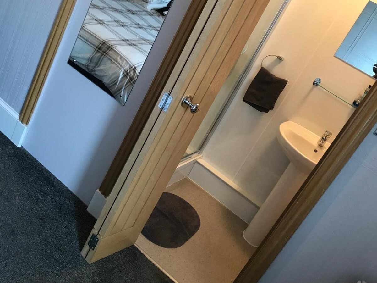 Casa de banho com lavatório, porta-toalhas e um tapete pequeno no chão.