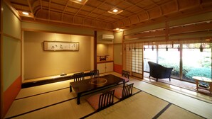 Um quarto japonês tradicional com tatames, uma mesa baixa e uma cadeira preta.
