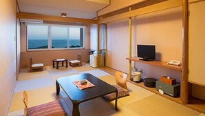 Um quarto japonês tradicional, com tatames, uma mesa baixa e uma televisão numa estante.