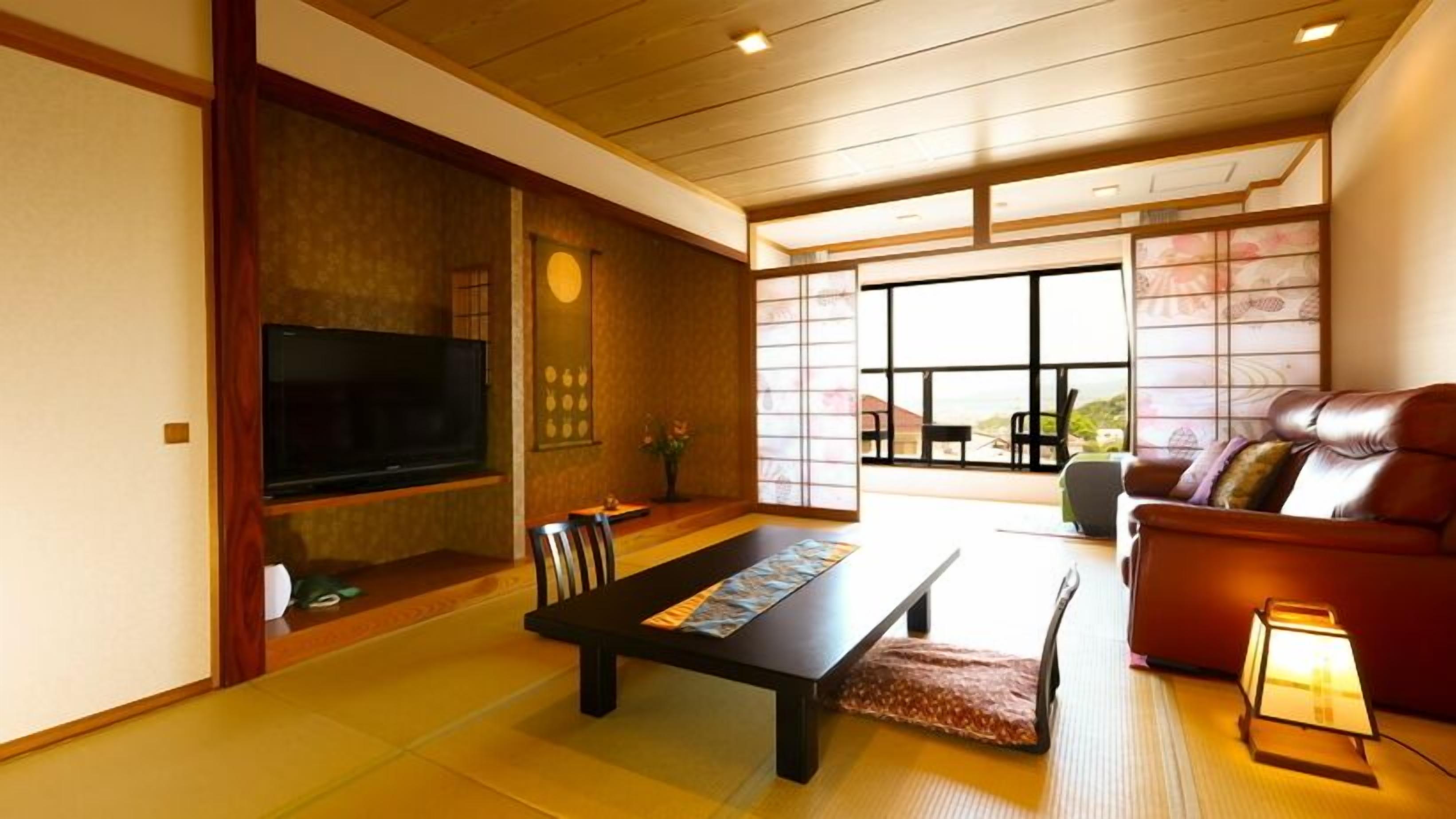 Uma sala de estar tradicional japonesa com tatames, uma mesa baixa, um sofá e uma televisão.