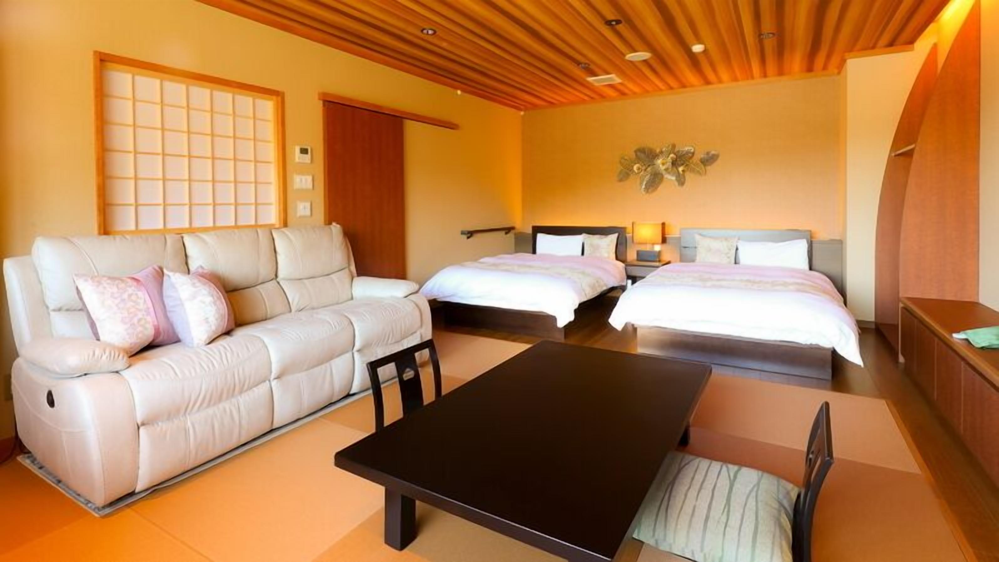 Quarto de hotel com sofá, duas camas, uma mesa e um objeto decorativo na parede.