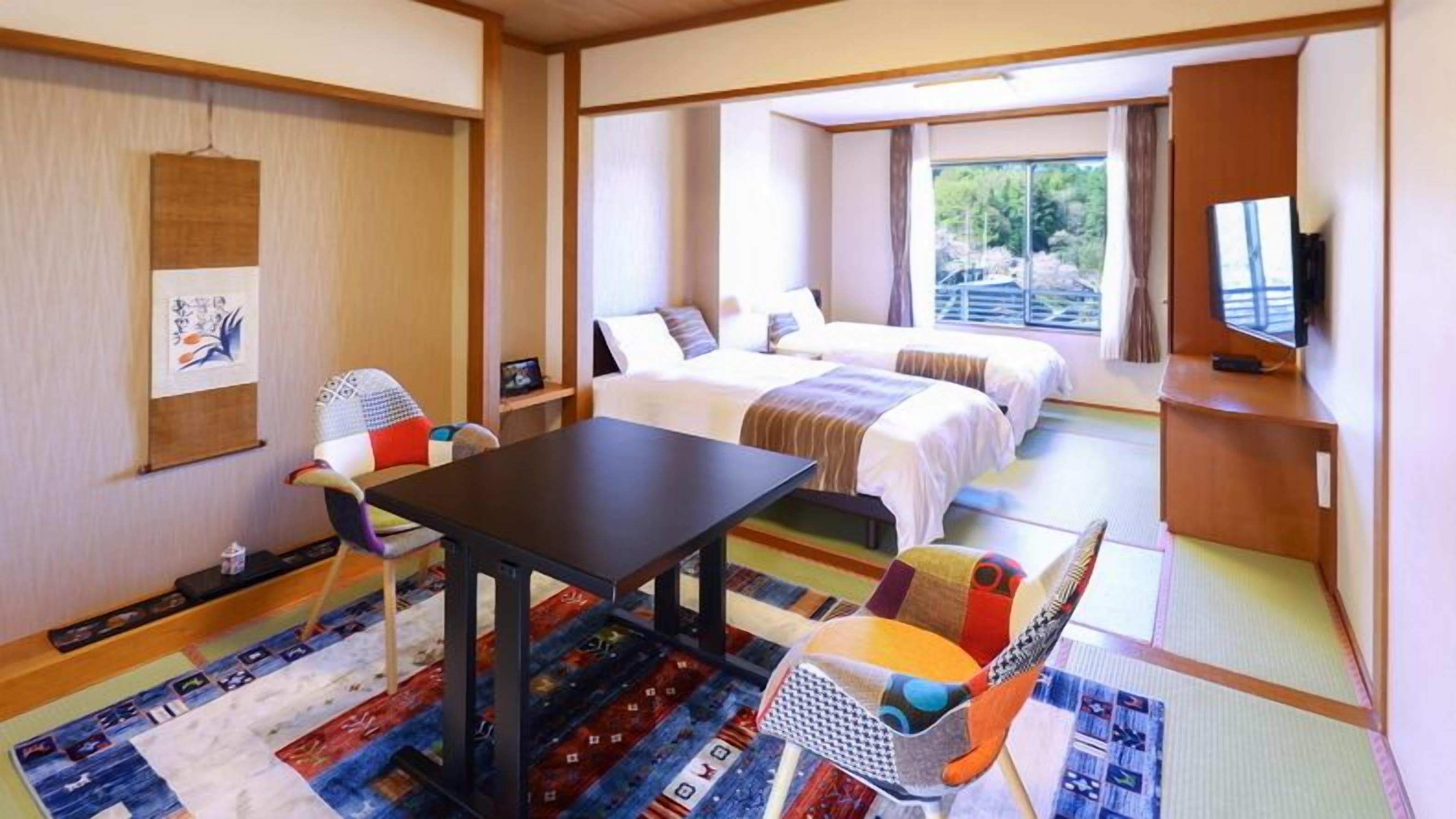 Quarto de hotel com uma cama, uma escrivaninha, uma cadeira e uma televisão.