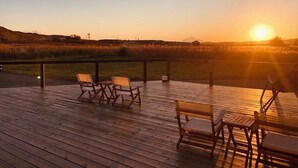 Um deck de madeira com assentos ao ar livre e vista para o pôr do sol.