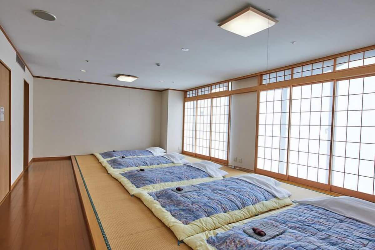Um quarto japonês tradicional com tatames, biombos shoji e futon.