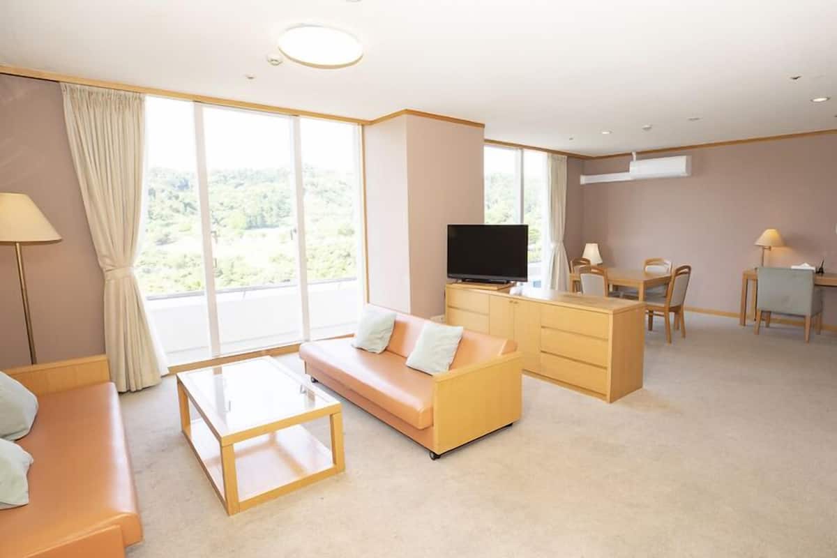 Uma sala de estar moderna com sofá, TV e área de refeições.