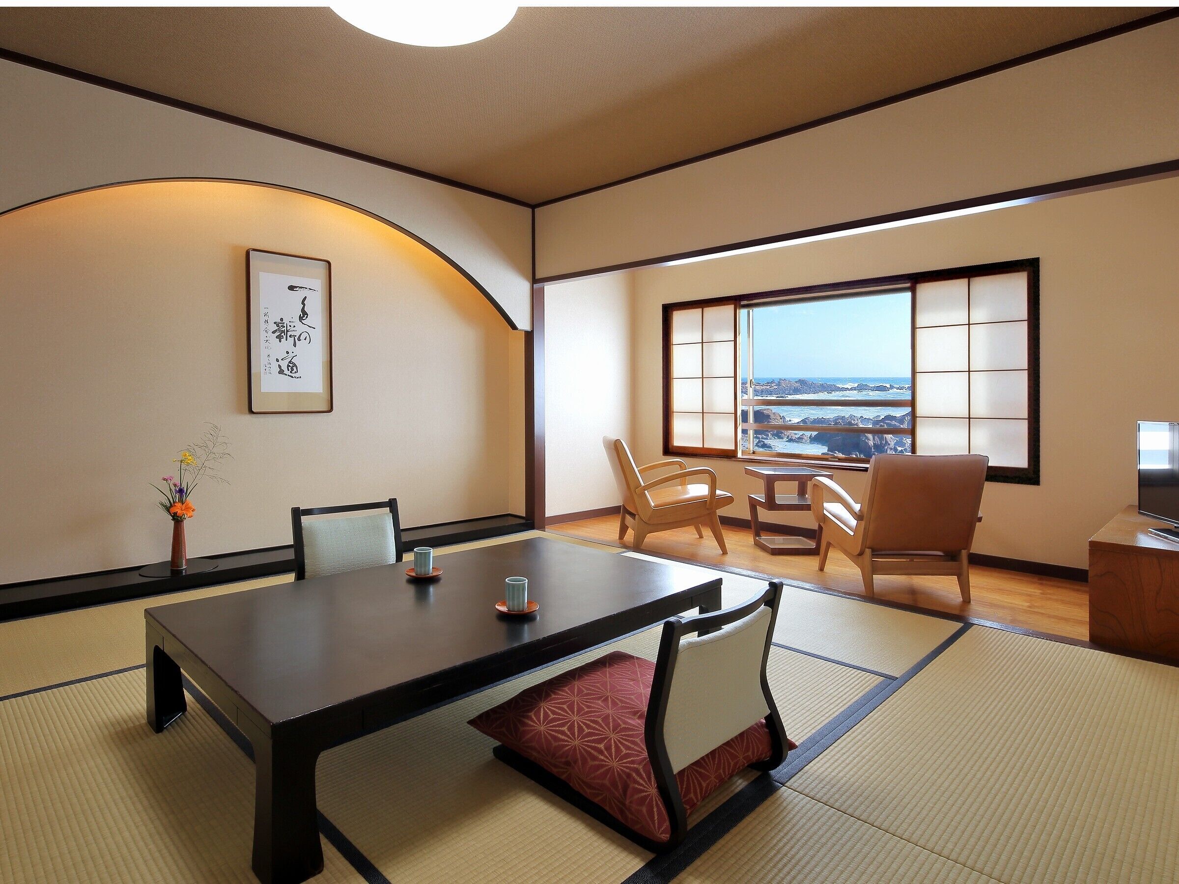 Um quarto japonês tradicional com tatames, uma mesa baixa e vista para o mar através de um shoji.