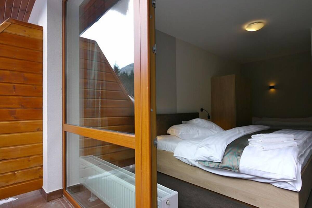 Quarto com cama, radiador e janela com vista para o exterior.