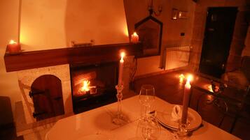 Um ambiente aconchegante com lareira, velas e mesa posta para refeição.