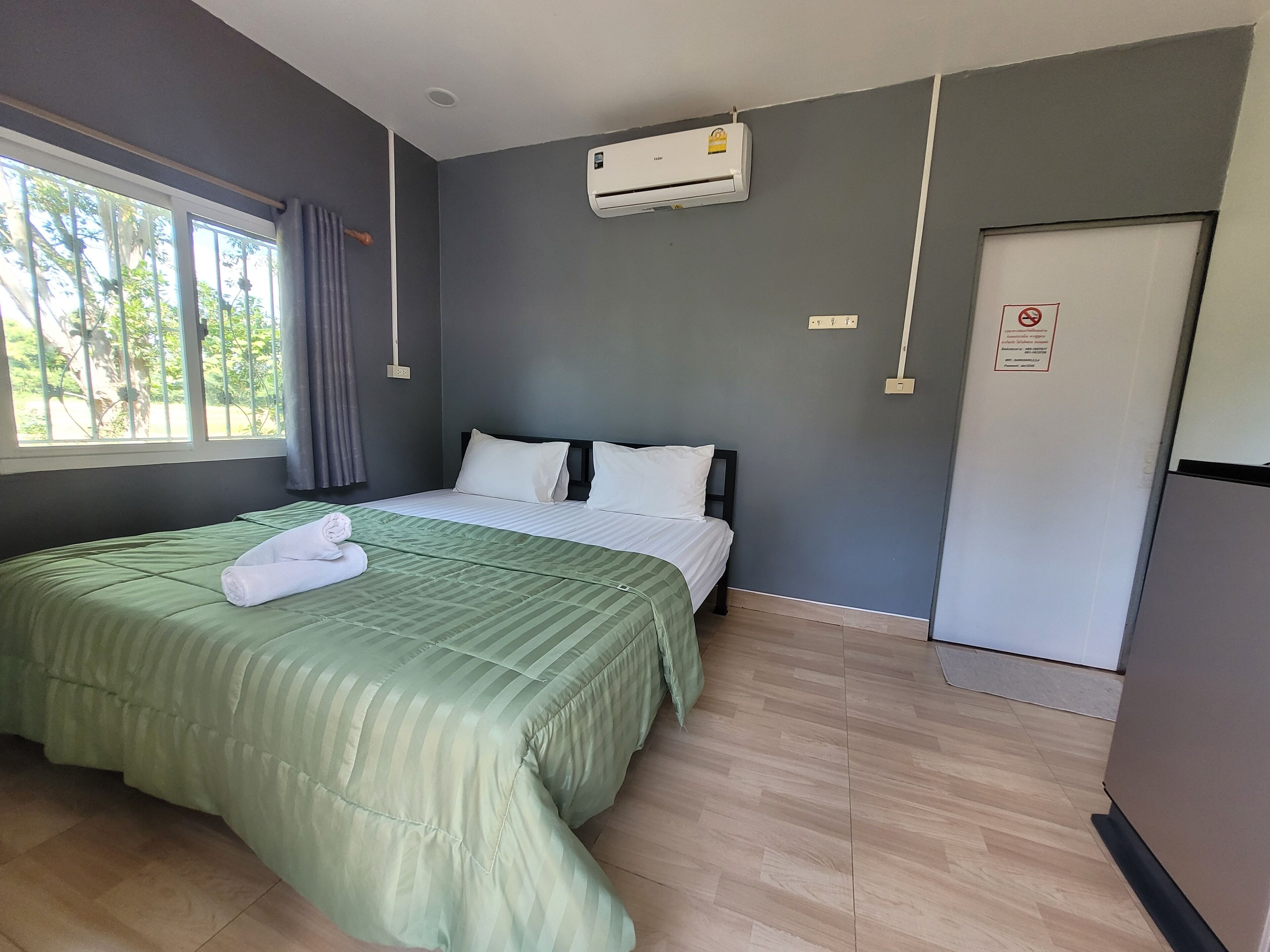 Quarto de hotel com cama, janela, ar condicionado e porta.