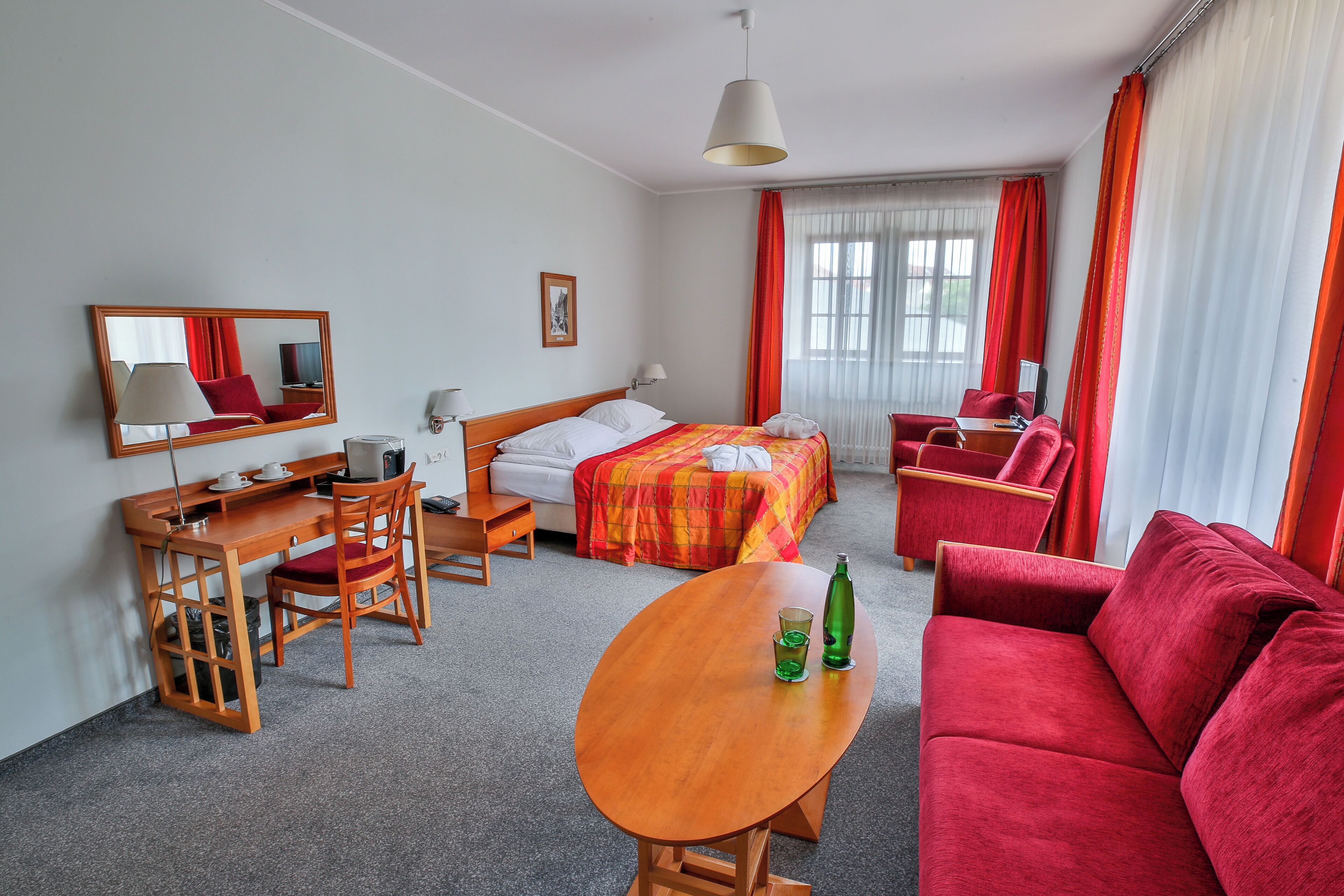 Quarto de hotel com uma cama, escrivaninha com cadeira, sofá e mesa.