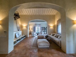 Uma sala de estar ampla com piso em padrão herringbone, um sofá, uma mesa de centro e uma lareira.