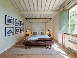 Um quarto com cama de dossel, quadros nas paredes e uma janela com cortinas.