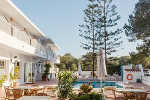 Um edifício moderno com área de piscina, espaço para sentar ao ar livre e escadaria que leva a um andar superior.