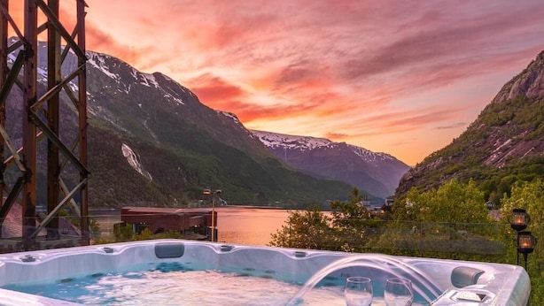 Uma banheira de hidromassagem com vista para as montanhas, uma vela e uma garrafa de champanhe.