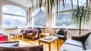 Uma sala de estar moderna com sofás de couro, mesas de centro de madeira e grandes janelas com vista para as montanhas.