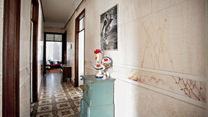 Um corredor com piso ladrilhado, um armário azul com objetos decorativos e um quadro na parede.