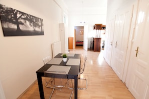 Uma área de refeições com mesa, cadeiras, uma planta pequena e um quadro na parede.