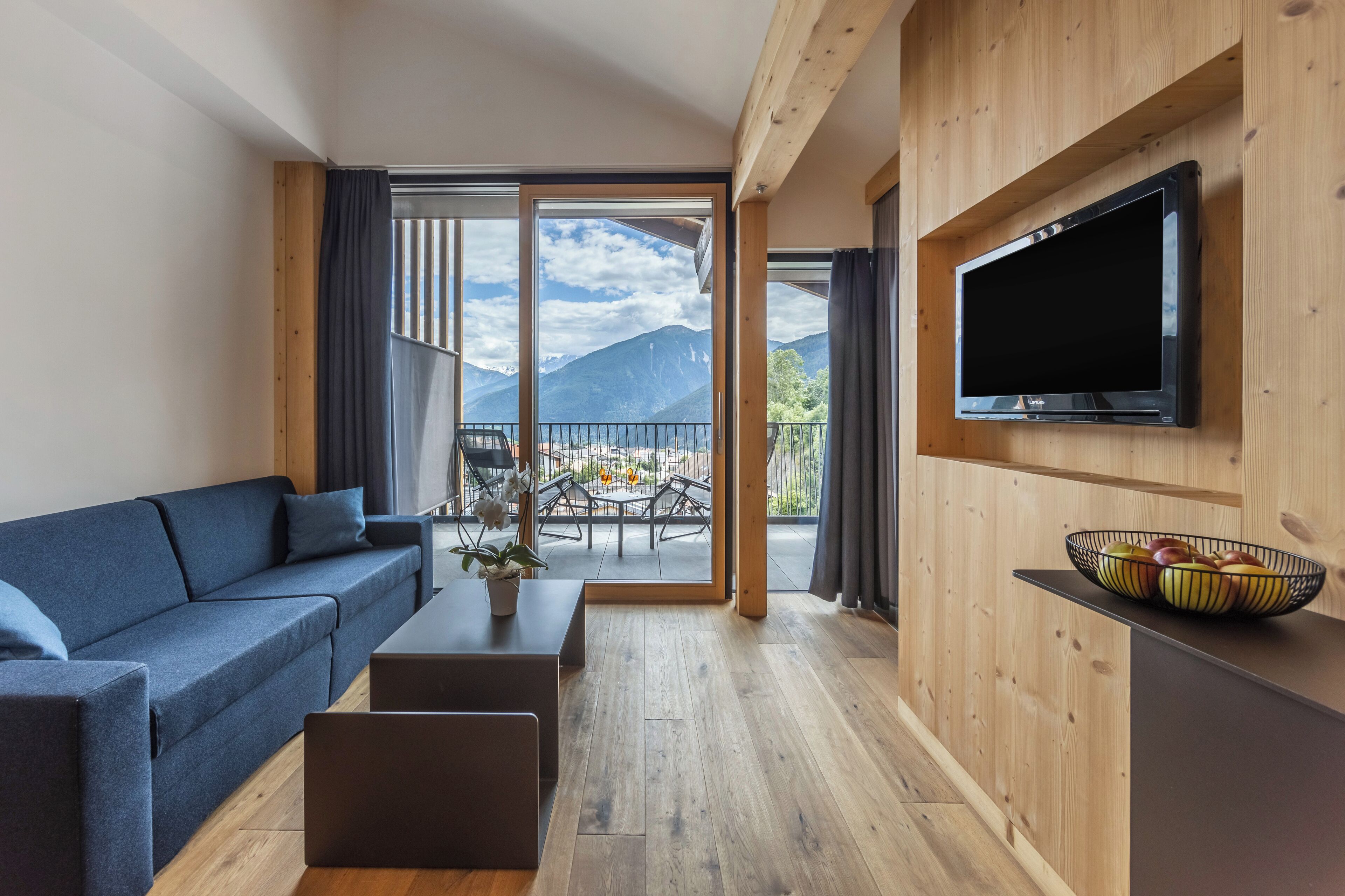 Uma sala de estar moderna com sofá, mesa de centro e uma televisão de tela plana fixada em uma parede de madeira.