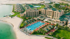 Um resort com uma piscina grande, acesso direto à praia e vários edifícios com telhados verdes.