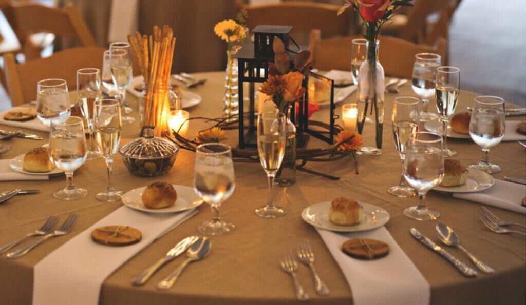 Uma mesa posta para refeição, com taças de vinho, pratos e talheres.