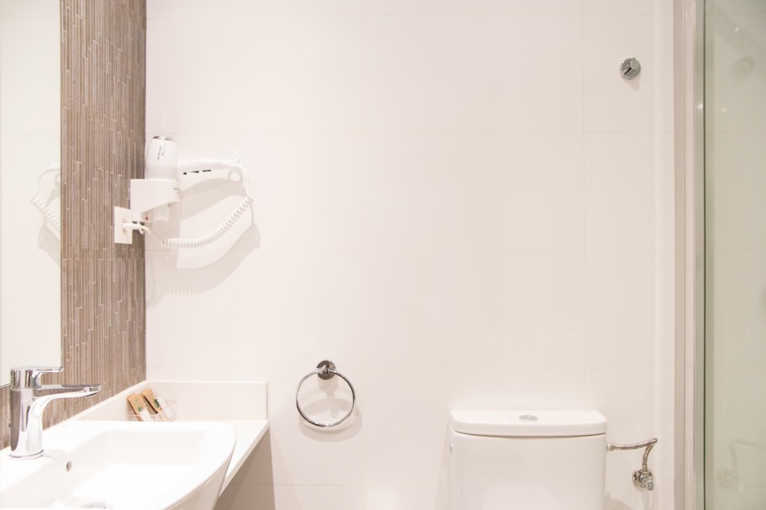 Um banheiro moderno com pia branca, box de vidro e vaso sanitário.