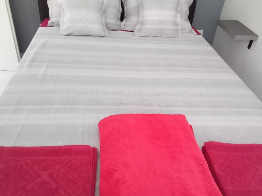 Cama com roupa de cama branca e duas almofadas vermelhas.