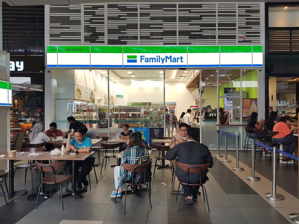 Um restaurante FamilyMart com mesas internas e um balcão de comida à mostra.
