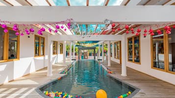 Área da piscina com vista clara, rodeada por colunas brancas e soalho de madeira.
