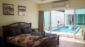 Quarto com uma cama grande, vista para uma piscina e duas pinturas na parede.