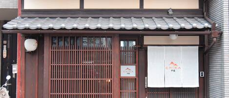 Um edifício japonês tradicional com telhado telhado, portas de correr de madeira e uma placa com a inscrição 'CHIKA'.