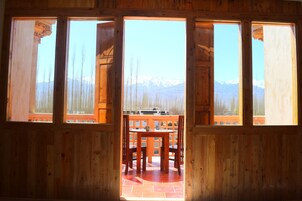 Uma cabana de madeira com uma grande janela com vista para uma cordilheira.