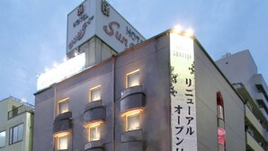 Um hotel com uma placa em japonês, várias janelas e uma varanda no andar superior.