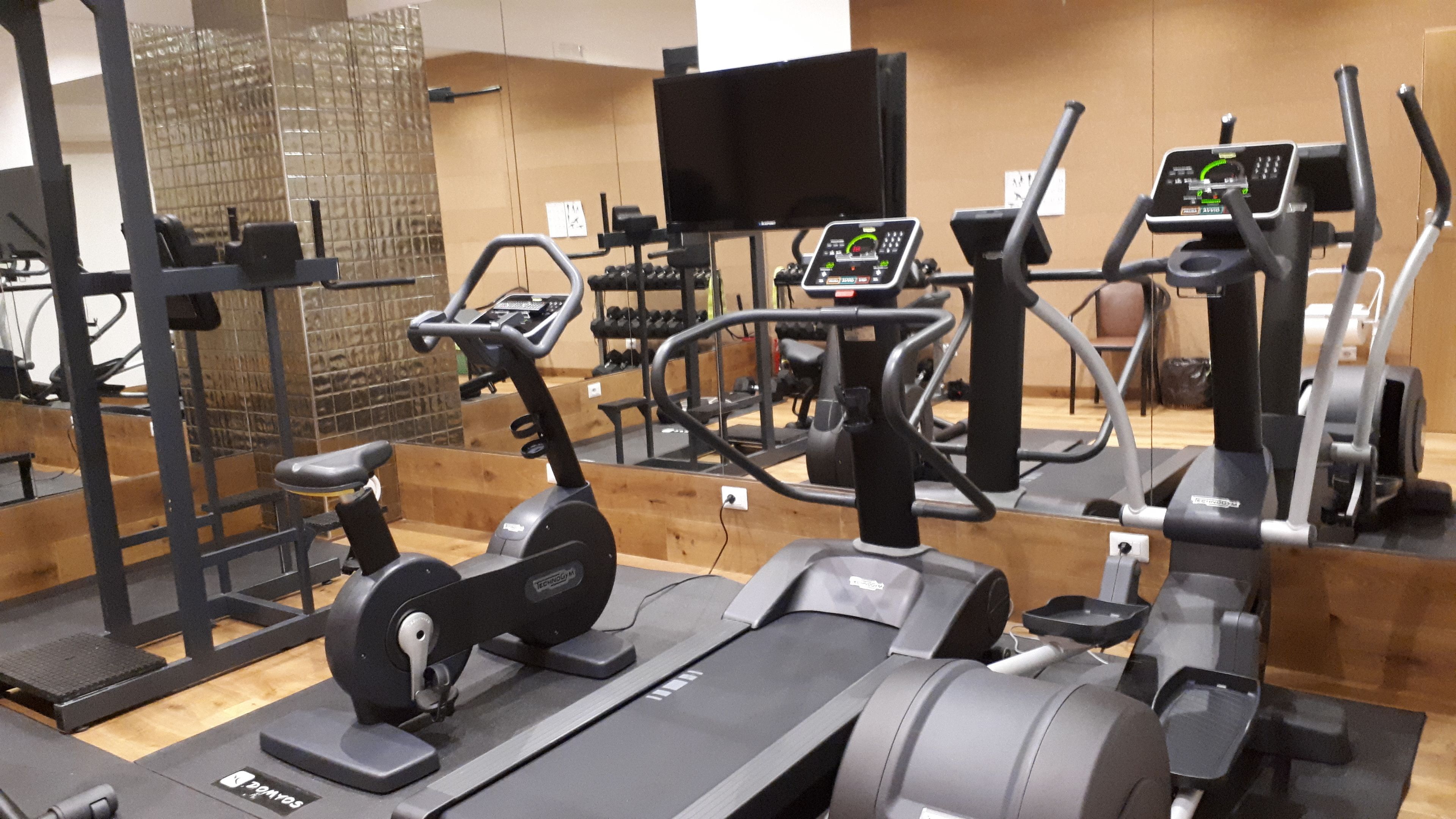 Uma academia com diversos equipamentos de exercícios, incluindo esteiras, bicicletas ergométricas e aparelhos de musculação.