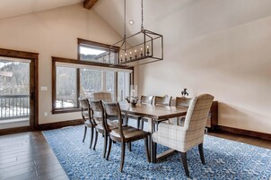 Uma sala de jantar com uma mesa de madeira, seis cadeiras e um lustre.