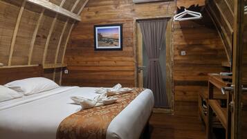 Um quarto acolhedor de madeira com uma cama, uma mesinha e uma porta.