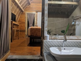 Interior em madeira com banheiro, incluindo pia, espelho e chuveiro.
