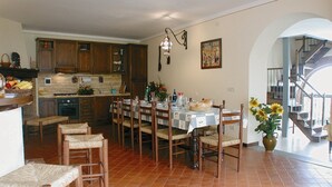 Uma cozinha ampla com armários de madeira, uma mesa de jantar posta para quatro pessoas e uma escada que leva a um andar superior.
