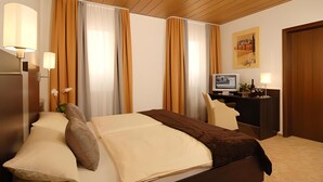 Quarto de hotel com uma cama, uma escrivaninha, uma televisão e um quadro na parede.