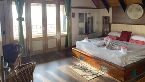 Quarto com cama de madeira, cortinas verdes, um espelho e um enfeite redondo na parede.