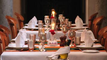 Mesa de jantar posta para refeição, com velas, copos e talheres.