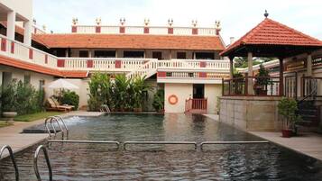 Piscina com boia, cercada por um edifício com varandas e área coberta.